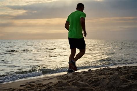 Premium Photo Back View Of Man Jogging Along Sea Beach At Morning