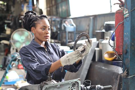 제복을 입은 여성 기술자 자동차 정비사가 정비소에서 정비 차량 서비스를 점검하고 있다 렌치 고정 고장 차량을 들고 있는 작업자