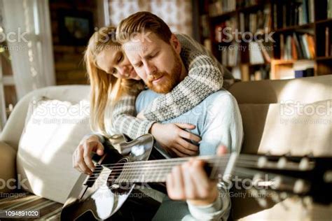 남자는 소파에 그의 젊은 아름 다운 여자를 위한 어쿠스틱 기타를 연주 가정의 방에 대한 스톡 사진 및 기타 이미지 가정의 방 거실 기타 현악기 Istock