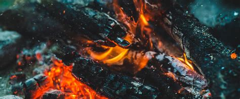 불에 타버린 생생한 연기가 나는 장작이 클로즈업되었습니다 모닥불의 주황색 불꽃이 있는 분위기 있는 배경 보케에 불꽃이 있는 모닥불의 전체 프레임 이미지 공기 중에 빛나는