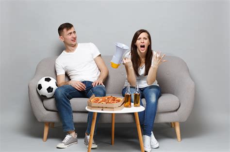 흰색 T 셔츠에 당황 비명 부부 여자 남자 축구 팬 지원 좋아하는 팀을 응원 회색 배경에 고립 된 확성기를 개최 사람들의 감정 스포츠 가족 레저 라이프 스타일 개념입니다