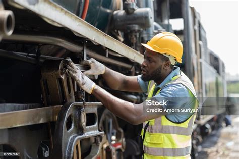 남성 엔지니어 유지 보수 기관차 엔진 기관차 수리 차고에서 안전 유니폼 헬멧 및 장갑을 착용 남성 철도 엔지니어는 기차 차고에서