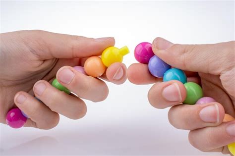 흰색 배경에 표정이 있는 색 구슬을 들고 있는 손 프리미엄 사진