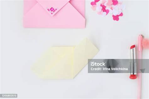 플랫 레이 종이 접기 기법에서 마음의 모양으로 접힌 분홍색 봉투 립스틱 펜 색종이 하트 노란색 종이 발렌타인 데이 엽서 만들기