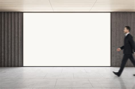 밝은 나무 천장과 회색 콘크리트 바닥 모형이 있는 빈 홀에서 로고 또는 텍스트를 위한 공간이 있는 빈 흰색 빛나는 화면을 걷는