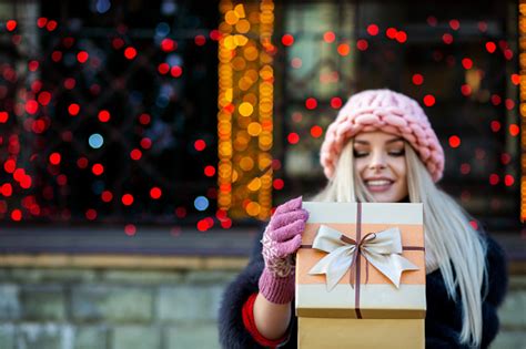 니트 모자와 따뜻한 코트를 입고 도시 조명의 배경에 선물 상자를 열고 행복한 금발 소녀 텍스트 공간 20 24세에 대한 스톡 사진 및 기타 이미지 Istock
