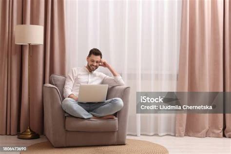집에서 아름 다운 커튼과 함께 창문 근처의 안락 의자에 노트북을 들고 웃는 남자 텍스트를 위한 공간 남자에 대한 스톡 사진 및 기타 이미지 Istock