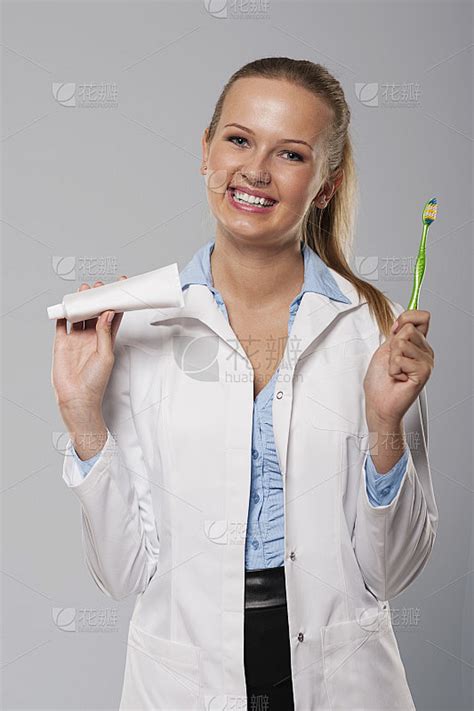 年轻的女牙医带着美丽的微笑拿着牙刷和牙膏
