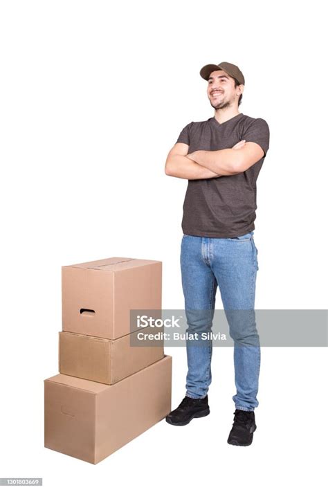 모자를 쓰고 있는 젊은 배달원 전체 길이의 초상화 흰색 배경에 고립된 소포 우편함 근처를 가로지르는 팔이 서 있다 택배 배달 패키지 우수한 고객 서비스 개념 고객에 대한