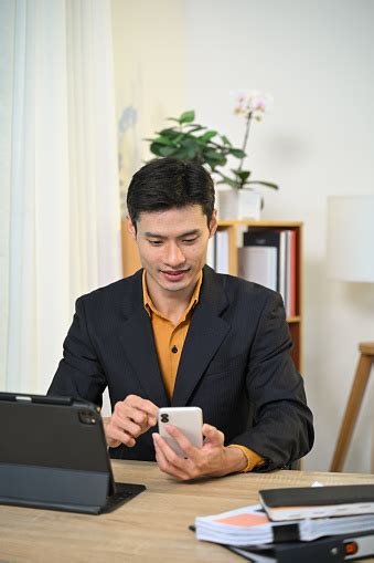 업무 중 스마트폰으로 메시지를 확인하는 잘생긴 아시아 사업가 25 29세에 대한 스톡 사진 및 기타 이미지 25 29세 30 34세 Brand Name Smart