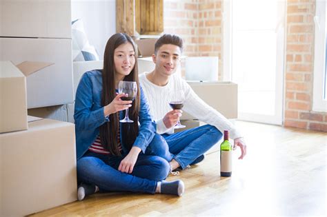 젊은 아시아 부부는 새로운 아파트 Arround 골판지 상자의 바닥에 앉아 새로운 집으로 이동에 대한 흥분 와인 한 잔을 마시는 미소 2명에 대한 스톡 사진 및 기타 이미지