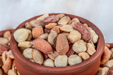 오래 된 소박한 테이블에 견과류와 말린 과일을 섞어 줍니다 골드 피스타치오 캐슈 헤이즐넛 아몬드 및 차 음식 배경입니다 0명에