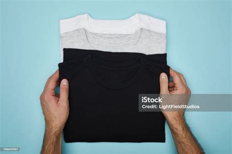 파란색으로 고립 된 빈 기본 블랙 화이트 및 회색 티셔츠를 만지는 남자의 자른 보기 T 셔츠에 대한 스톡 사진 및 기타 이미지