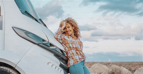 현대 캠핑카 밴 캠핑카에 맞서 행복한 성인 여성 관광객이 미소를 지으며 카메라를 바라본다 여성 여행자는 목적지와 휴가를