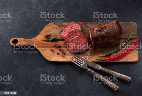 로즈마리와 칠리 페퍼를 곁들인 나무 판에 구운 쇠고기 콘크리트 검은 색 배경 최고 전망 고기에 대한 스톡 사진 및 기타 이미지 고기 구이 굽기 Istock