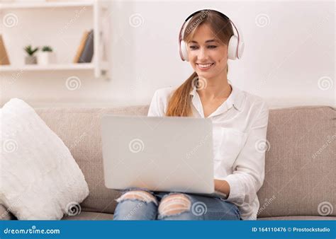 Girl Using Laptop Listening To Podcast Sitting On Couch Indoor Stock