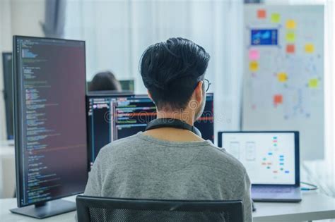 Asian Software Developers Working On Multiple Screens Displaying Code And Application Diagrams