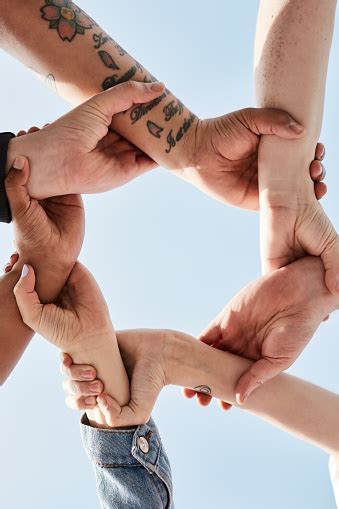 손 연결 연결 및 팀 서클에있는 사람들과의 신뢰와 연대 지원 및 협업 야외 커뮤니티 팀워크 및 사명 다양성 및 하늘 배경을 가진 친구들과의 목표 25 29세에 대한 스톡