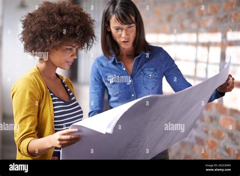 Lets Put This Plan To Use Two Female Architects Discussing Blueprints While Standing Inside A