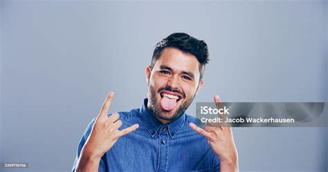 공간 행복 또는 회색 배경에 야생 표정을 위해 스튜디오에서 바위 손 제스처를 가진 남자의 초상화 문화 날카로운 남성 로커와 악마 뿔 기호 펑키 이모티콘 및 펑크 상징을 가진