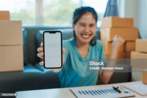 모형을 위한 빈 흰색 모바일 화면을 보여주는 손 Sme 패키지 상자를 들고 있는 아시아 여성 스마트폰을 사용하여 온라인 이메일 주문 채팅 상자 메시지 Sme 판매자를 받는