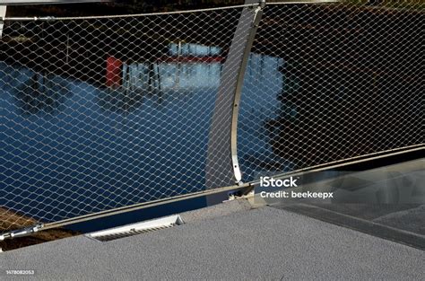 구멍이 뚫린 금속 바닥이 있는 계단과 넓은 보행자 다리 원형 구멍이있는 아연 도금 판금 아치에있는 배와 같은 흰색 난간 광택 스테인레스 스틸 파이프로 만든 난간 철망에 대한