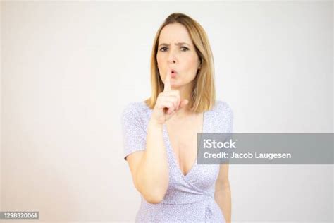 고립된 흰색 배경 위에 서있는 아름답고 젊은 여성의 초상화는 입술에 손가락으로 조용히 할 것을 요구합니다 침묵과 비밀 개념 귀여운에 대한 스톡 사진 및 기타 이미지 Istock