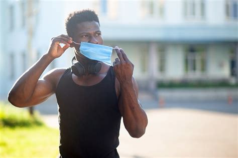 아프리카계 미국인 남자는 도시의 배경 코로나바이러스 전염병에 있는 사람들을 배경으로 야외에서 의료용 마스크를 착용합니다 수술용 마스크에 대한 스톡 사진 및 기타 이미지