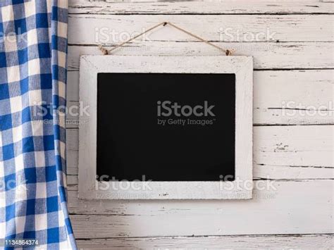 오래 된 흰색 풍 화 된 티크 나무 액자 칠판은 보드의 왼쪽에 매달려 파란색 체크 깅 엄 소재 식탁보와 오래 된 흰색 풍 화 티크 나무 패널 벽 배경에 대 한 오래 된