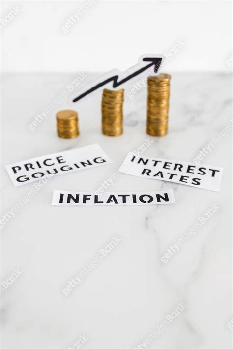 Inflation Interest Rates And Price Gouging Texts In Front Of Growing Stacks Of Coins With Arrow