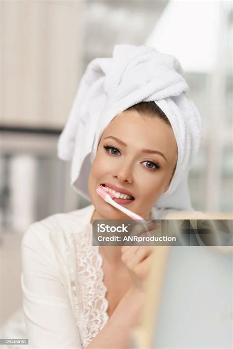 한 여성이 이빨을 닦고 있습니다 아침 구강 위생 복사 공간을 클로즈업합니다 매력적인 소녀 와 A 목욕 수건 에 그녀의 머리 후 A 아침 샤워 양치질에 대한 스톡 사진 및