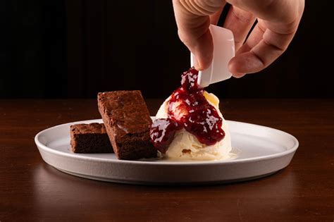 바닐라 아이스크림의 달콤한 디저트 브라우니 2장과 요리사 손 넣어 빨간 과일 시럽 건강에 좋지 않은 음식에 대한 스톡 사진 및 기타 이미지 건강에 좋지 않은 음식