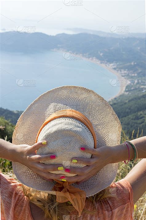 女孩戴着草帽从山景看海边