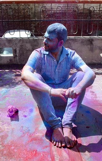 힌두교 인도 남자의 이미지는 멀티 컬러 페인트 파우더로 덮여 셔츠와 청바지에 지붕 상단에 앉아 색상 사진 홀리 축제 그림