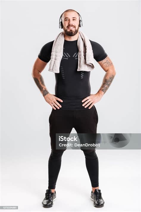 스포츠 후 목에 허리와 수건을 손에 들고 서있는 동안 헤드폰을 통해 음악을 듣는 근육질의 전체 길이 사진 흰색 배경에 고립 강사에 대한 스톡 사진 및 기타 이미지 Istock