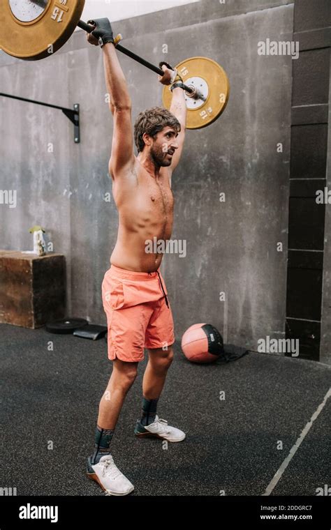 Side View Of Muscular Male Athlete Doing Clean And Jerk Exercise While Training In Modern