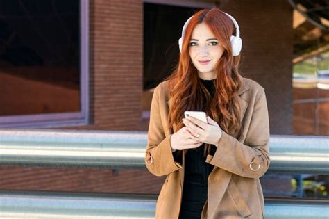 Premium Photo Young Redhaired Girl Looking Into The Camera With Wireless Headphones And