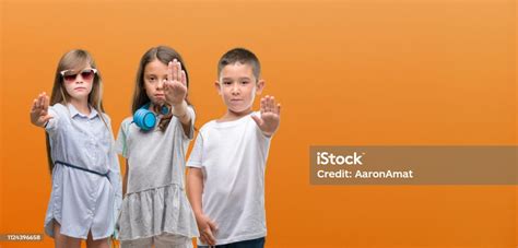 심각 하 고 자신감 있는 표현 방어 제스처와 중지 표시를 하 고 오픈 손으로 오렌지 배경 위에 소년과 소녀 아이 들의 그룹 경계 표지에 대한 스톡 사진 및 기타 이미지