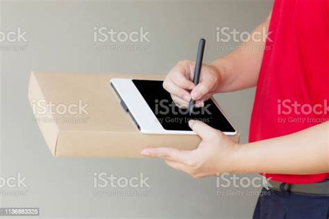 우편 배달 부는 갈색의 배경에 소포 상자를 들고 서 영수증에 서명 하는 태블릿을 건네 섰다 과로에 대한 스톡 사진 및 기타 이미지 Istock