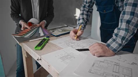 Two Men Sharing A Table Inspecting A Drawing Of A Building 53652558