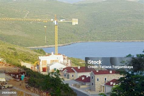 해안에 부동산 건설 바다와 산을 배경으로 건설중인 타워 크레인 자재 및 주택의 전망 0명에 대한 스톡 사진 및 기타 이미지