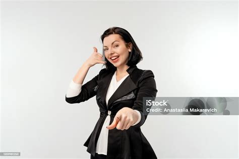 검은 색 정장 재킷 흰색 셔츠에 미소 젊은 사업가의 초상화는 카메라에 손가락을 가리키는 휴대 전화 제스처를 보여주는 나에게 전화 흰색 배경 위에 서 30 34세에 대한 스톡