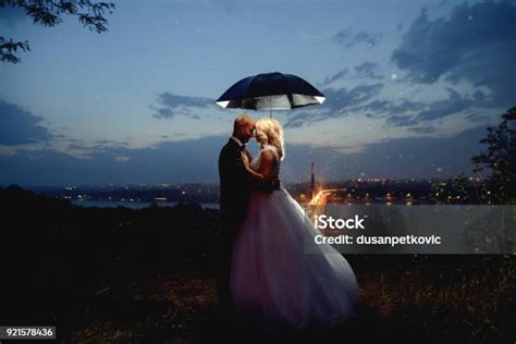 낭만적인 사랑의 부부 신혼 밤 하늘의 배경 결혼식 그것은 비가 신랑과 신부는 서 우산 아래 사랑에 Bokeh 웅덩이 방울 플래시 그들의 뒤에 교량입니다 2명에 대한 스톡