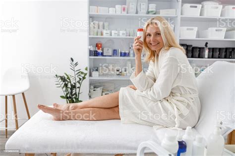흰 목욕 가운을 입고 미소짓는 백인 여성 미용실에서 크림 항아리를 들고 있는 백인 여성 45 49세에 대한 스톡 사진 및 기타 이미지 45 49세 각질제거 건강관리와