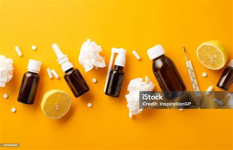 계절성 질병 개념 구제 스프레이 및 시럽 투명 갈색 병의 톱보기 사진 냅킨 정제 캡슐 온도계를 구겨 내고 고립 된 오렌지색 배경에 레몬을 자릅니다 레몬에 대한 스톡 사진 및