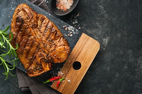 생 스테이크 Tbone 또는 포터 하우스 스테이크 Tbone 또는 포터 하우스는 콘크리트 배경에 검은 세라믹 플레이트에 향신료 소금 및 로즈마리를 곁들인 소스에 담았습니다