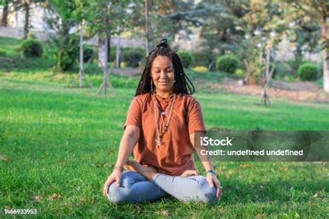 젊은 여자는 연꽃 자세로 앉아 공원에서 명상하고 있다 건강한 생활 방식의 개념입니다 땋은 머리에 대한 스톡 사진 및 기타 이미지 땋은 머리 35 39세 건강한 생활