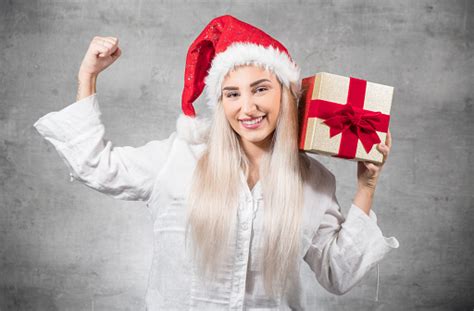 행복 아름다운 금발 의 여자 는 크리스마스 산타 클로스 모자를 착용 모자와 빨간 선물 상자를 들고 회색 배경에 고립 된 리본 선물 20 24세에 대한 스톡 사진 및 기타