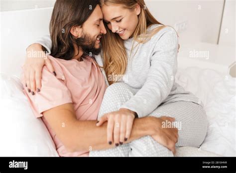 Photo Of Cute Happy Positive Young Loving Couple In Bed Hugging Indoors