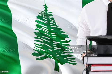 성공적인 학생 교육 개념입니다 노퍽 섬 국기 배경 위에 책과 졸업 모자를 들고 교사 교육 관련 직업에 대한 스톡 사진 및 기타 이미지 교사 교육 관련 직업 교육 기